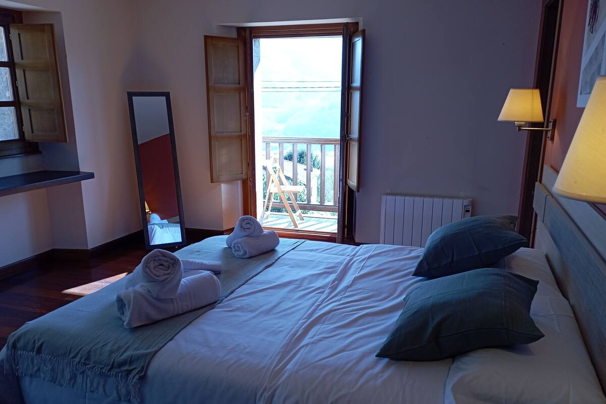 Quarto de hotel com cama, duas almofadas, toalha, janela e varanda.