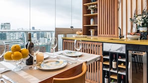 Uma sala de jantar moderna com uma mesa de madeira posta para dois, uma garrafa de vinho e uma taça com limões.