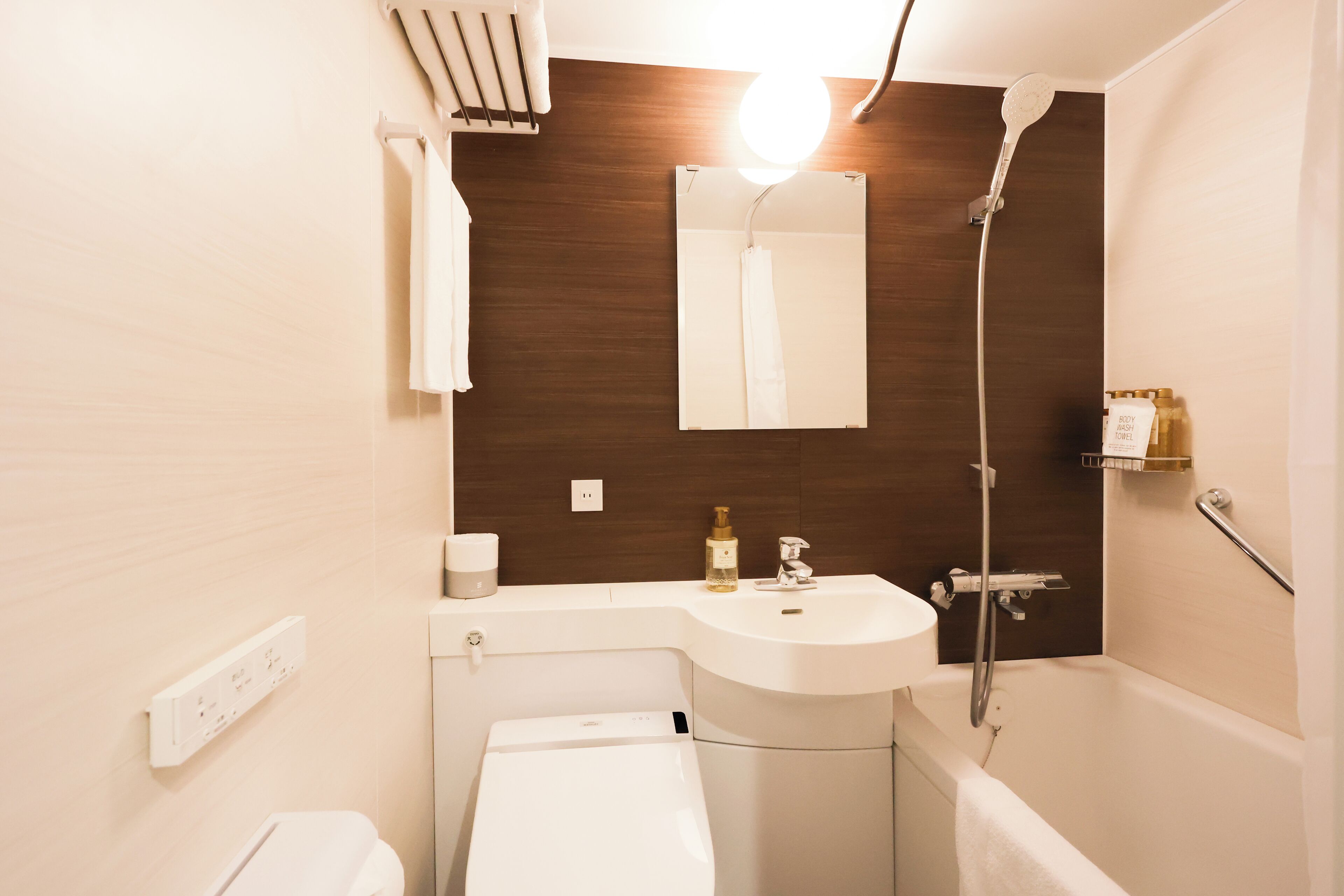 Casa de banho moderna com lavatório branco, espelho, chuveiro e sanita.