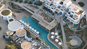 Vista aérea de um resort com várias piscinas, áreas de estar ao ar livre e paisagismo exuberante.