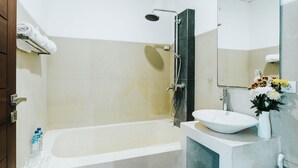 Casa de banho com banheira, lavatório e espelho.