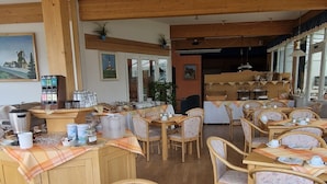 Um restaurante com vigas de madeira, mesas montadas com pratos, copos e talheres.