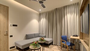 Uma sala de estar moderna com um sofá cinzento, uma poltrona azul e uma pequena mesa com flores.