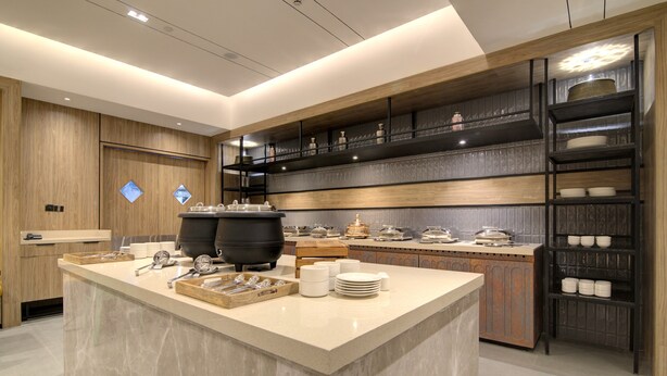 Cozinha moderna com bancada de mármore, armários de madeira e máquina de café preta.