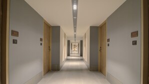 Um corredor longo e estreito em um hotel, com portas numeradas 302 e 303, que dão acesso aos quartos.