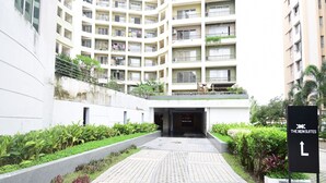 Um edifício moderno com várias varandas, uma entrada central e uma placa com a inscrição "The Xenos Suites".