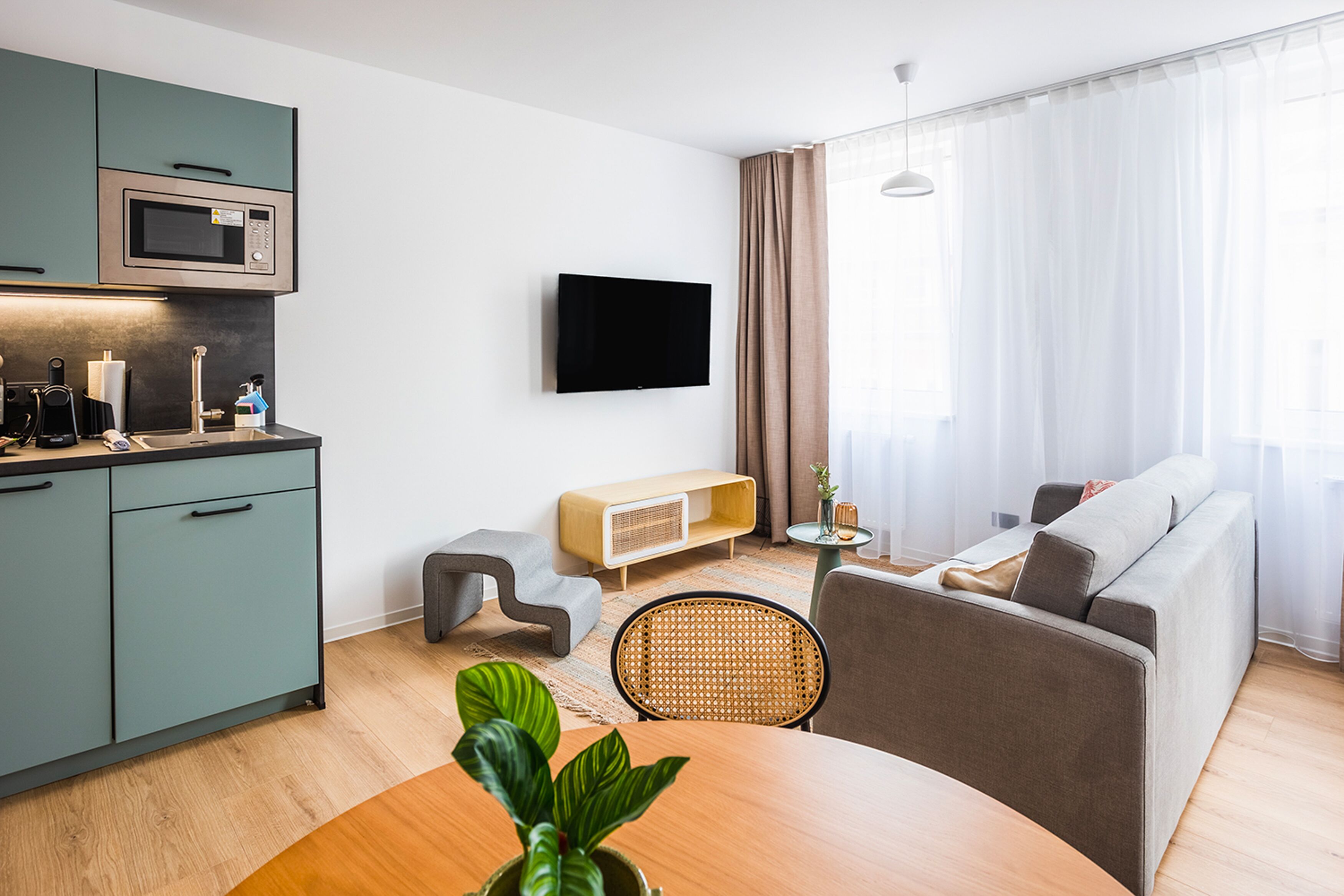 Uma sala de estar moderna com sofá, televisão e área de jantar com mesa e cadeiras.