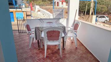 Uma varanda com mesa e cadeiras, um letreiro de restaurante e vista para uma encosta.