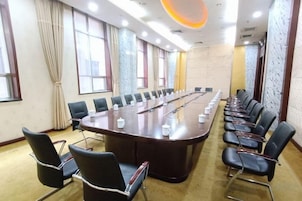 Uma sala de conferências com uma mesa comprida, cadeiras e piso coberto de carpete.