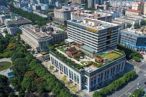 Um edifício com vários andares, um jardim no terraço e uma placa grande.