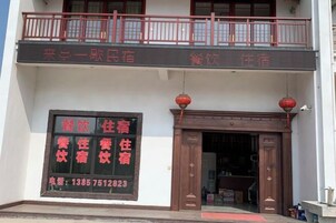 Entrada de hotel com varanda, placa com caracteres chineses e um lanterna vermelha.