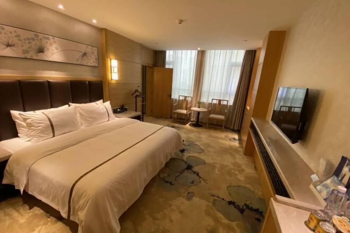 Quarto de hotel com uma cama grande, televisão de tela plana, uma mesa pequena e uma cadeira.