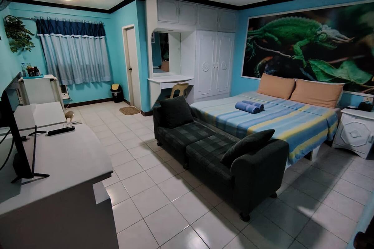 Um quarto com cama, escrivaninha, cadeira e guarda-roupa.