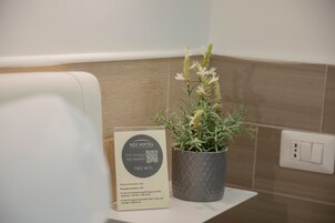 Uma área de recepção com placa indicativa do Hotel H22, um código QR e um vaso de planta.