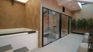 Um interior moderno com balcão de recepção, paredes de vidro e área de estar com plantas.