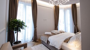 Quarto de hotel moderno com uma cama grande, uma planta em vaso e um candelabro.
