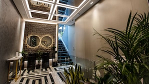 Um interior moderno com design geométrico no teto, uma escadaria e plantas em vasos.