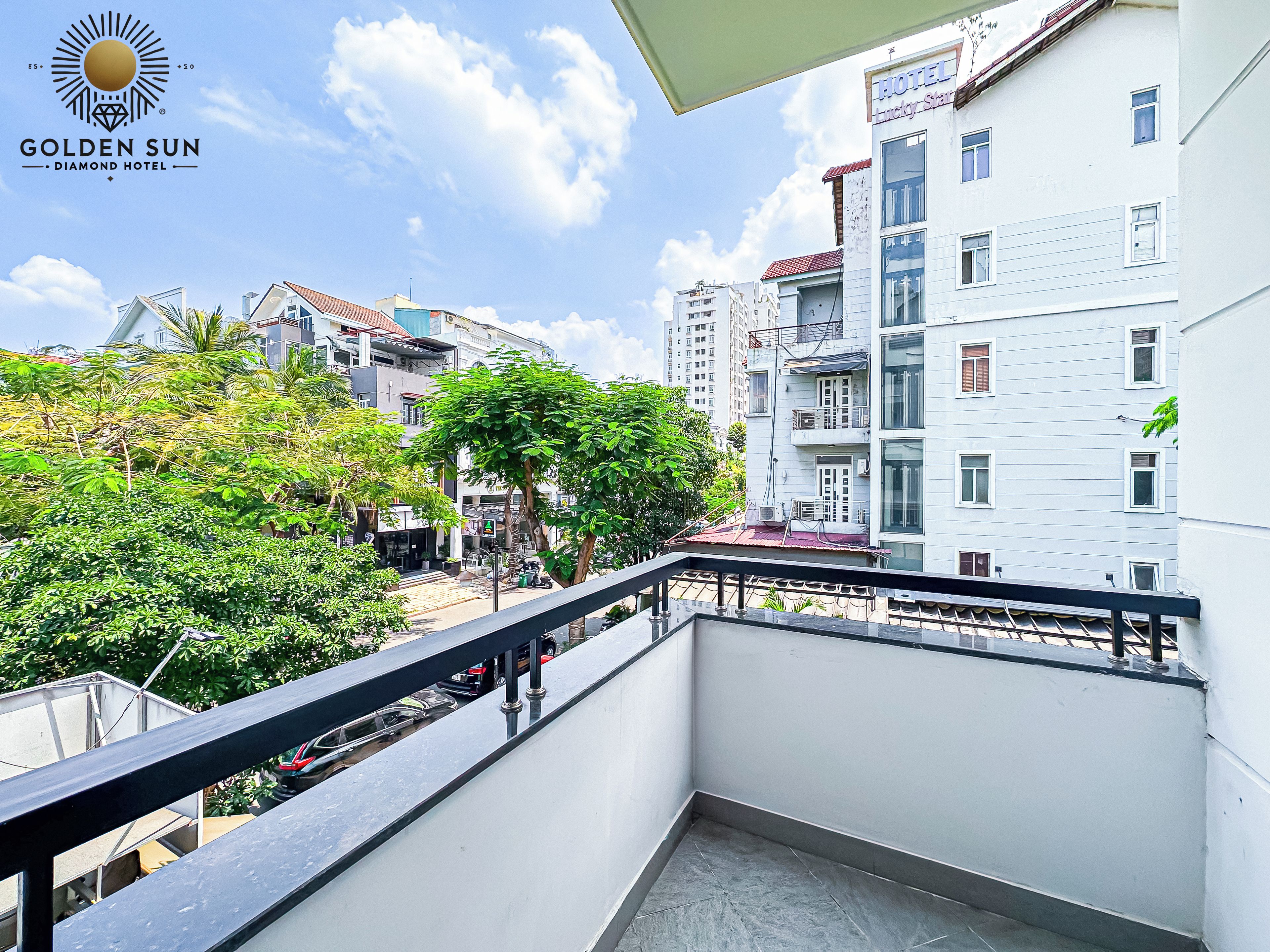 Uma varanda com vista para um horizonte urbano, incluindo um hotel chamado 'Lucky Star' e outros edifícios.