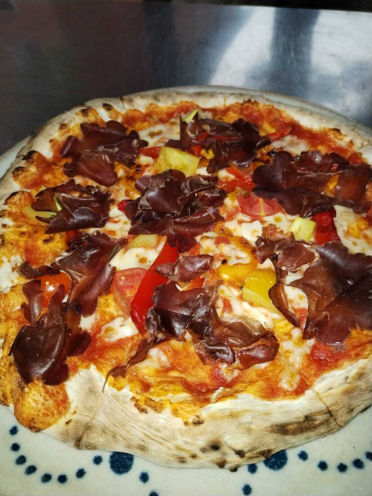 Pizza com diversos ingredientes sobre um prato branco.