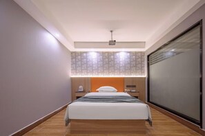 Quarto de hotel moderno com uma cama grande, projetor no teto e uma janela ampla com vista.