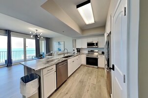 Uma cozinha moderna com uma ilha grande, eletrodomésticos de aço inoxidável e vista para o exterior.