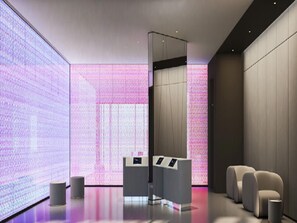 Um hall moderno com balcão de recepção, área de estar e grandes painéis digitais.