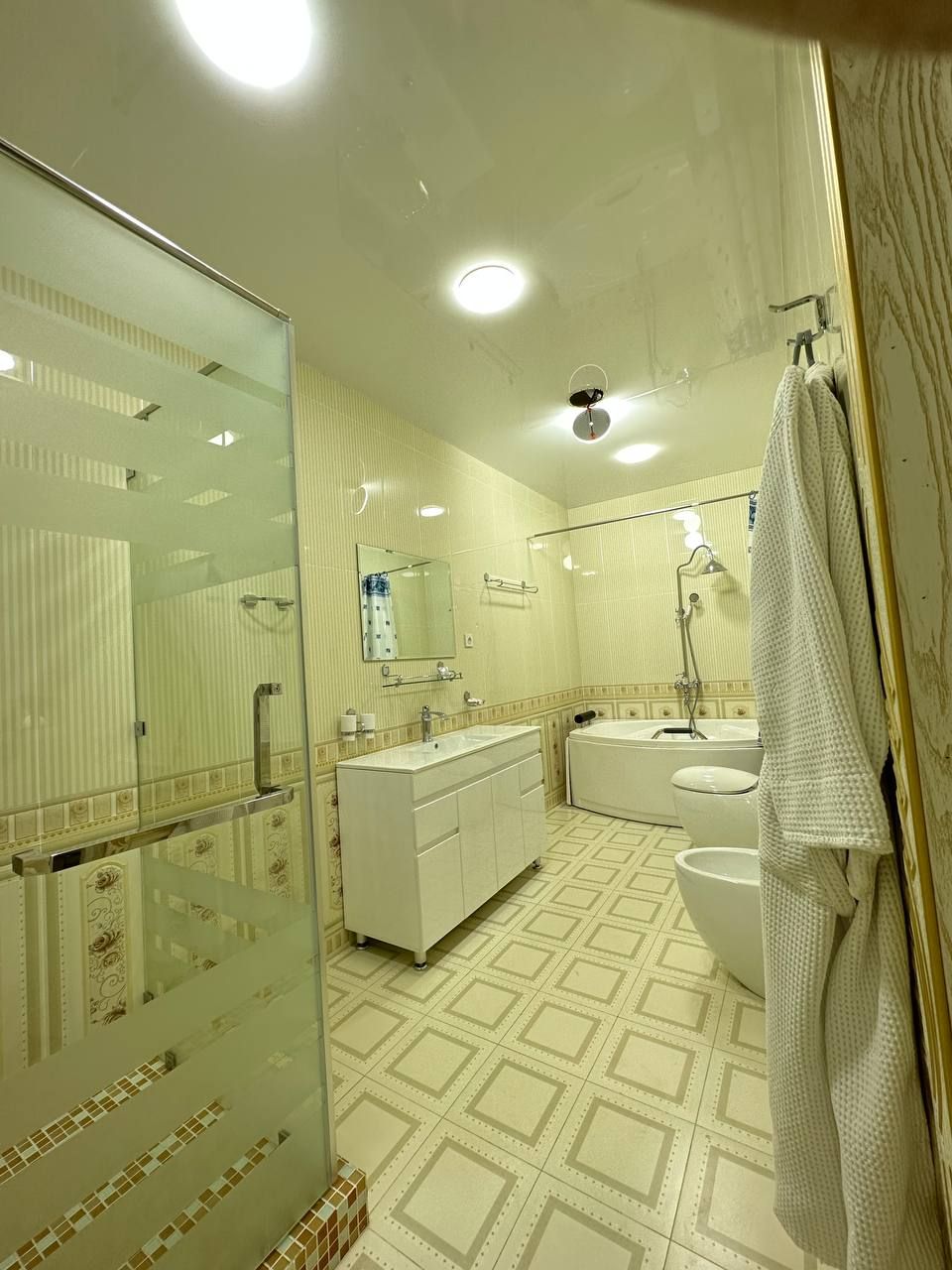 Um banheiro com chuveiro de vidro, pia branca, banheira e vaso sanitário.