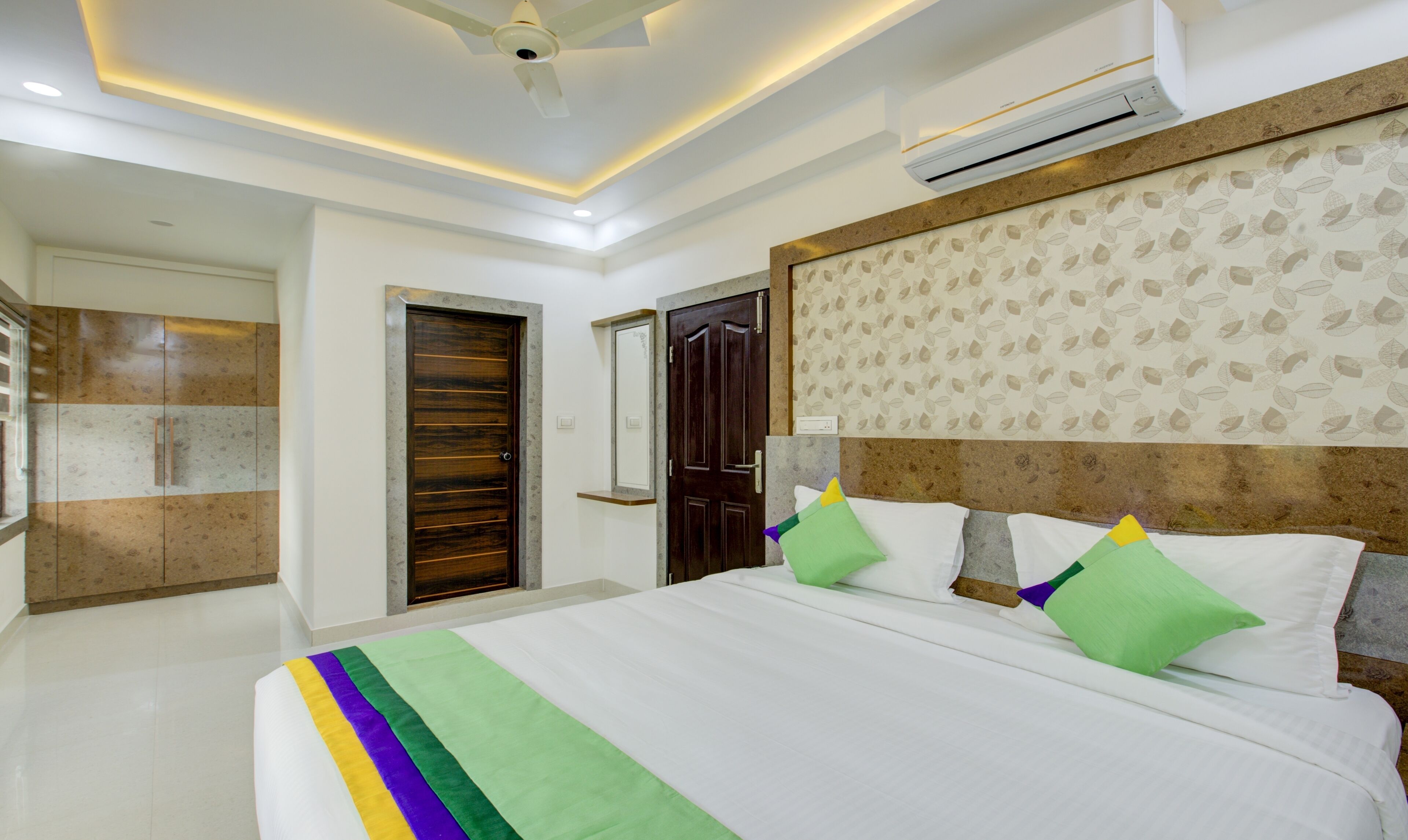 Quarto de hotel com cama, armário, porta e unidade de ar condicionado.