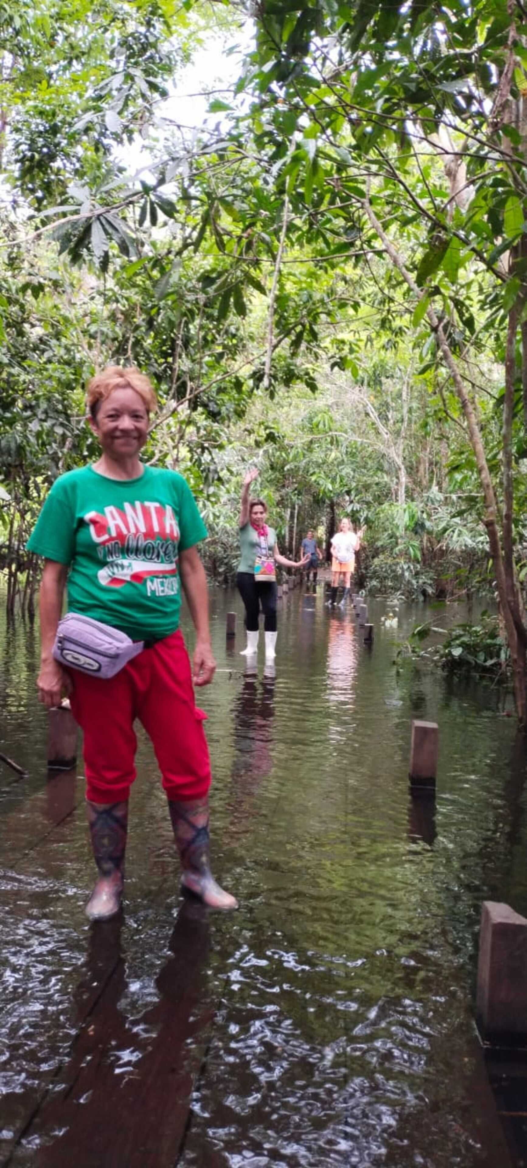Uma pessoa em área inundada, com árvores e água.