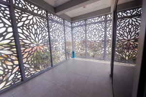 Uma varanda espaçosa com um design geométrico moderno, janelas amplas e piso ladrilhado.
