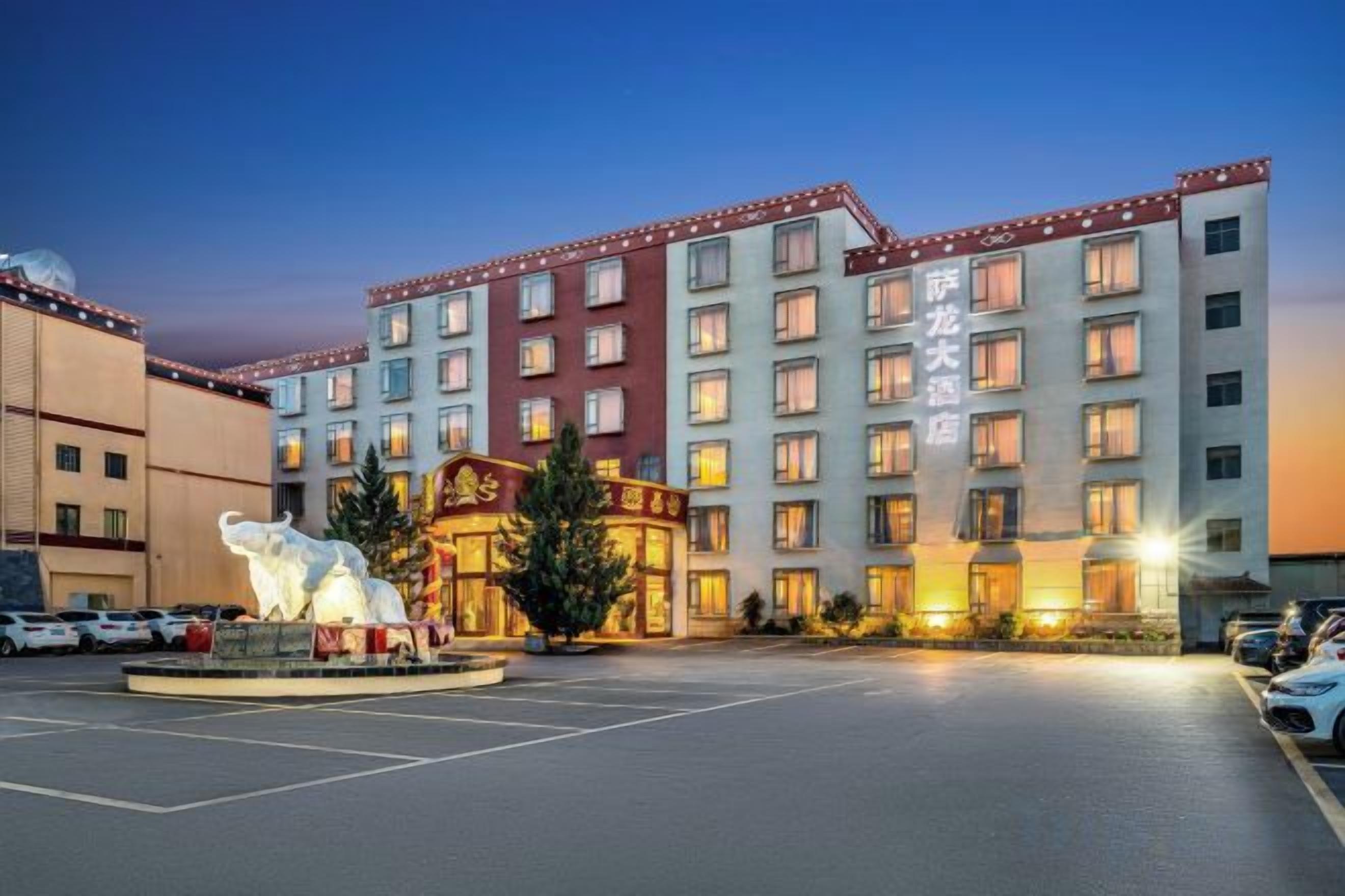 Hotel com vários andares, um pátio central, uma grande escultura e estacionamento.