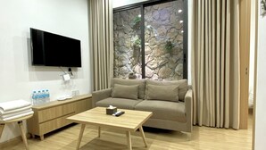 Uma sala de estar moderna com uma TV de tela plana, um sofá, uma mesa de centro e um painel de parede de pedra.