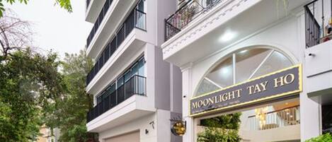 Um hotel de vários andares com uma placa indicando "MOONLIGHT TAY HO".