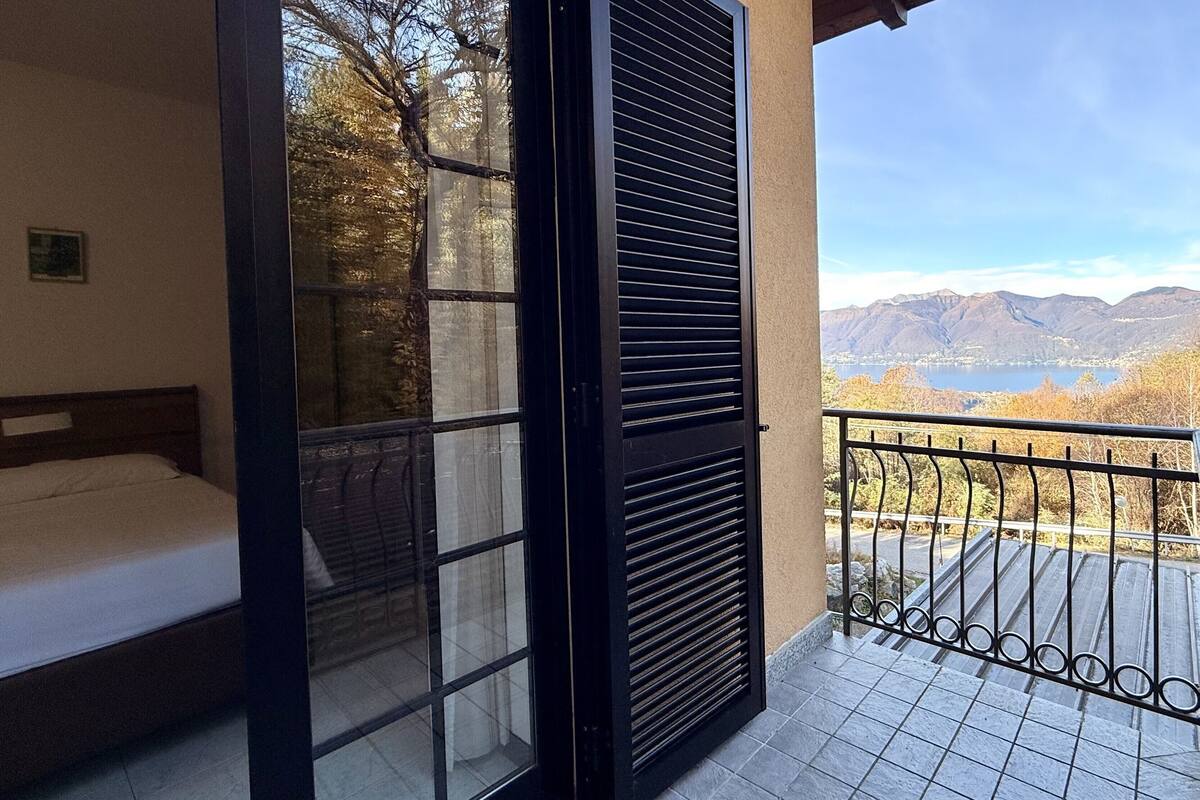 Uma varanda com uma cama, vista para montanhas e um lago.