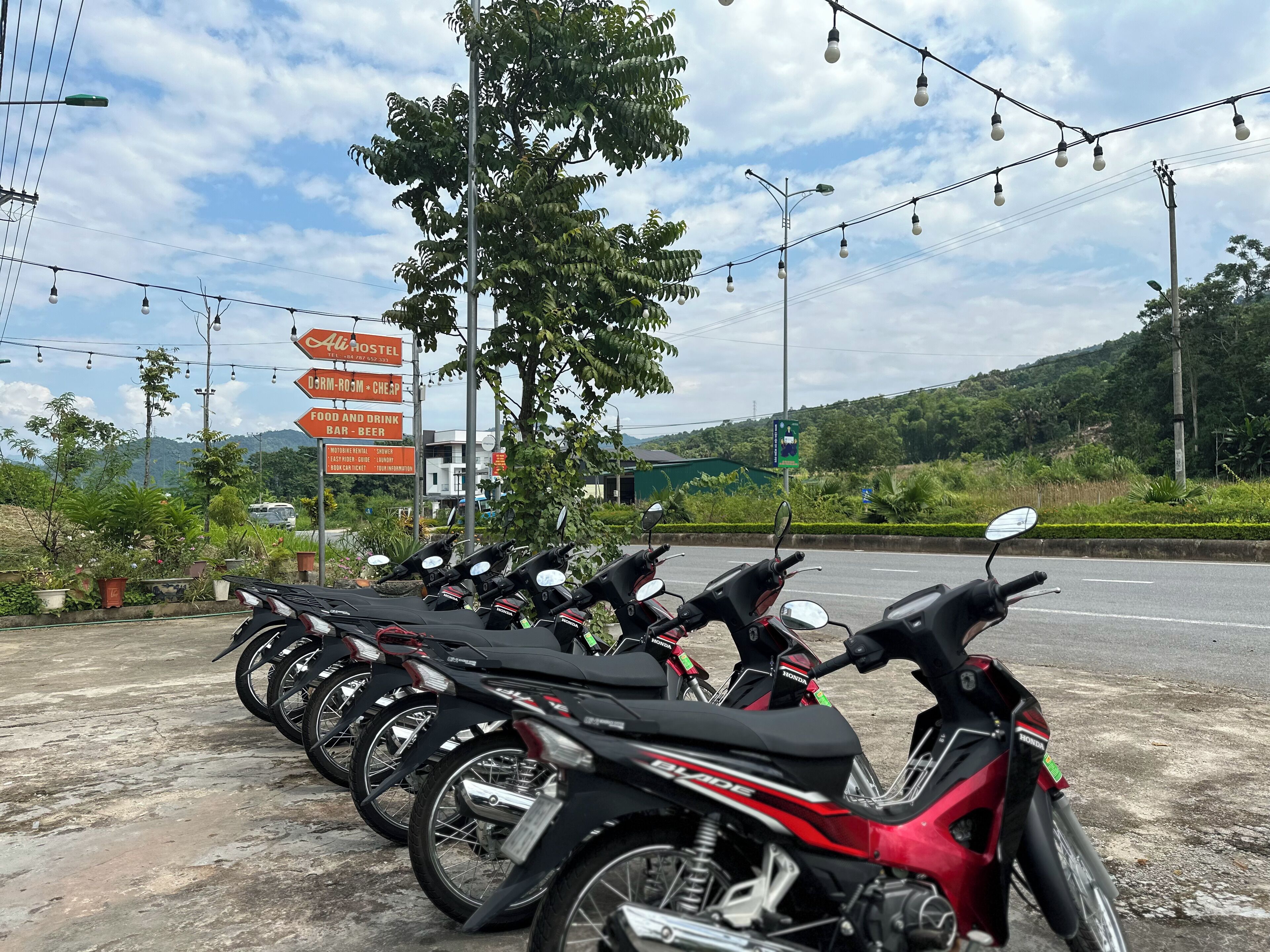 Motocicletas estacionadas, placa de um hostel e painel com diversos serviços.
