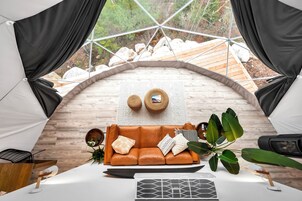 Uma tenda com piso de madeira, um sofá de couro marrom e uma mesa branca com teclado.