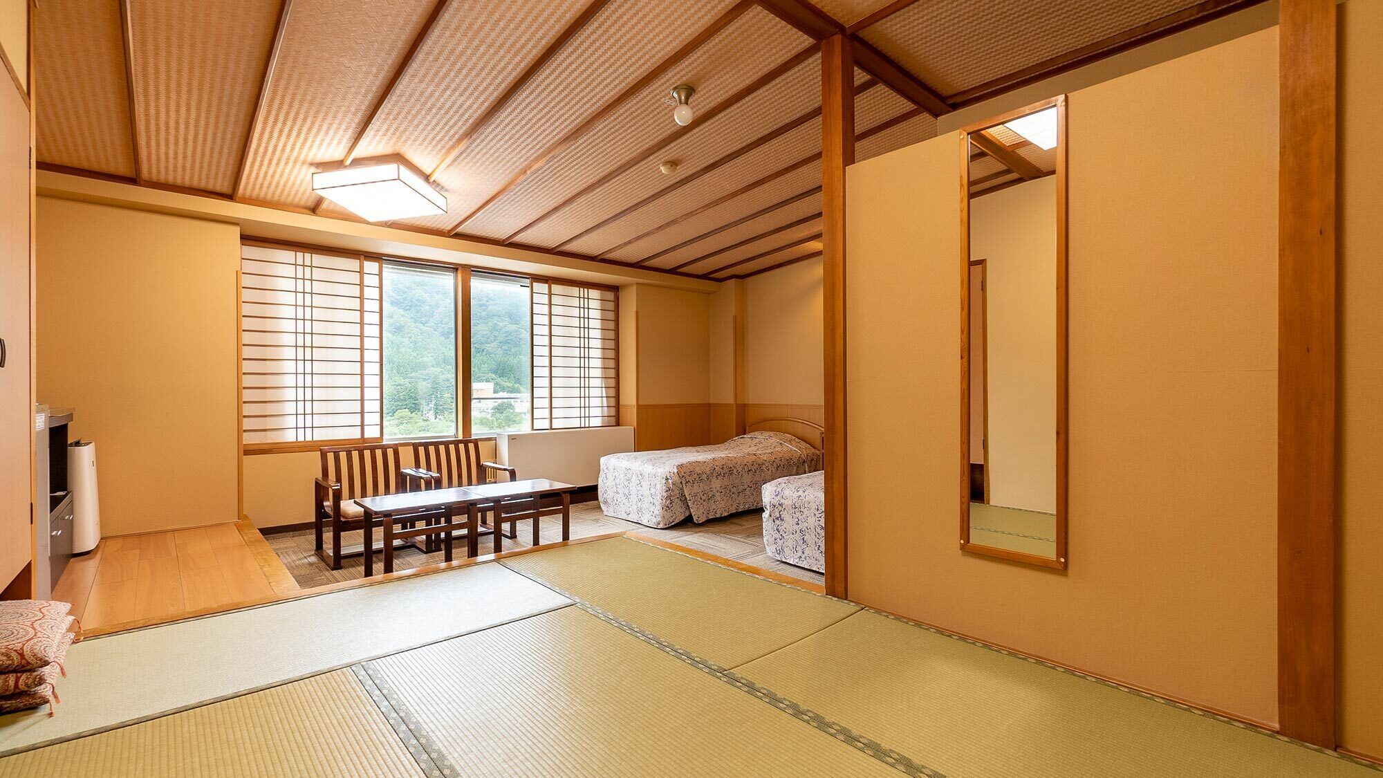 Um quarto japonês tradicional com tatames, uma mesa baixa, um sofá e uma cama.