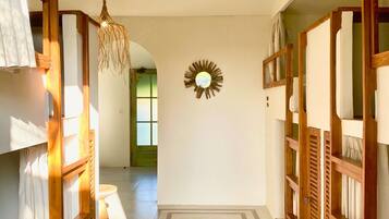 Um corredor com moldura de porta de madeira, luminária pendente e espelho embutido com design de sol.