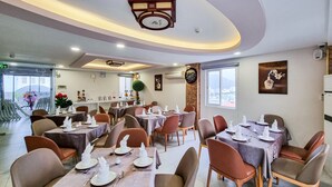 Restaurante com várias mesas preparadas para refeições, com pratos, talheres e guardanapos.
