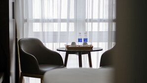 Quarto com duas cadeiras e uma pequena mesa com um tabuleiro de copos e garrafas de água.