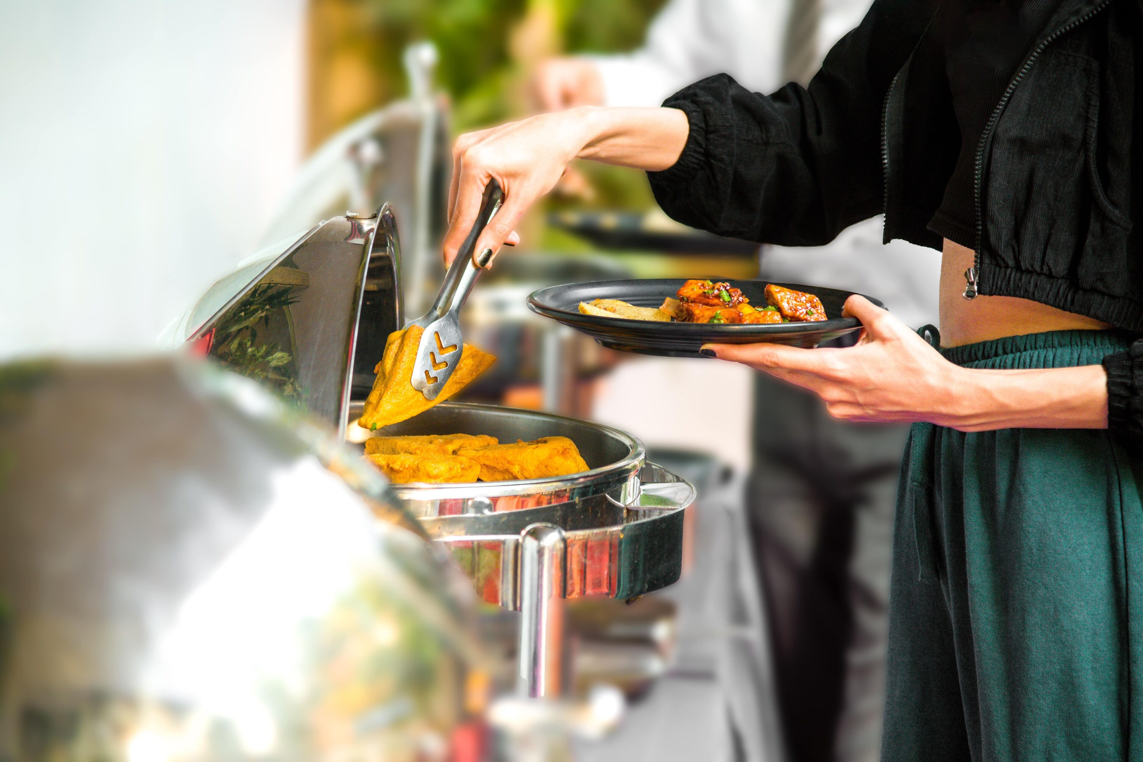 Disposição de buffet com uma pessoa servindo comida de uma panela.