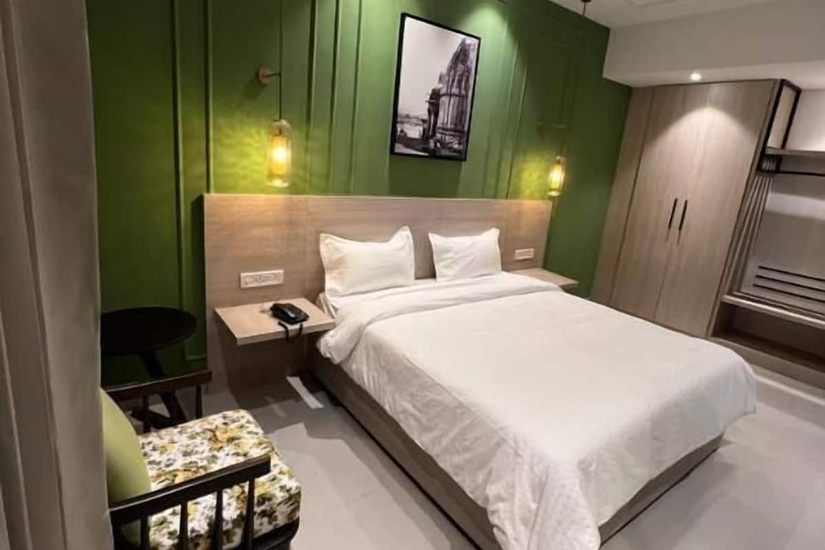 Quarto moderno com cama, mesas de cabeceira, uma cadeira e um guarda-roupa.