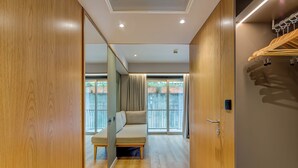 Quarto moderno com piso de madeira, banco embutido e uma grande janela com cortinas.
