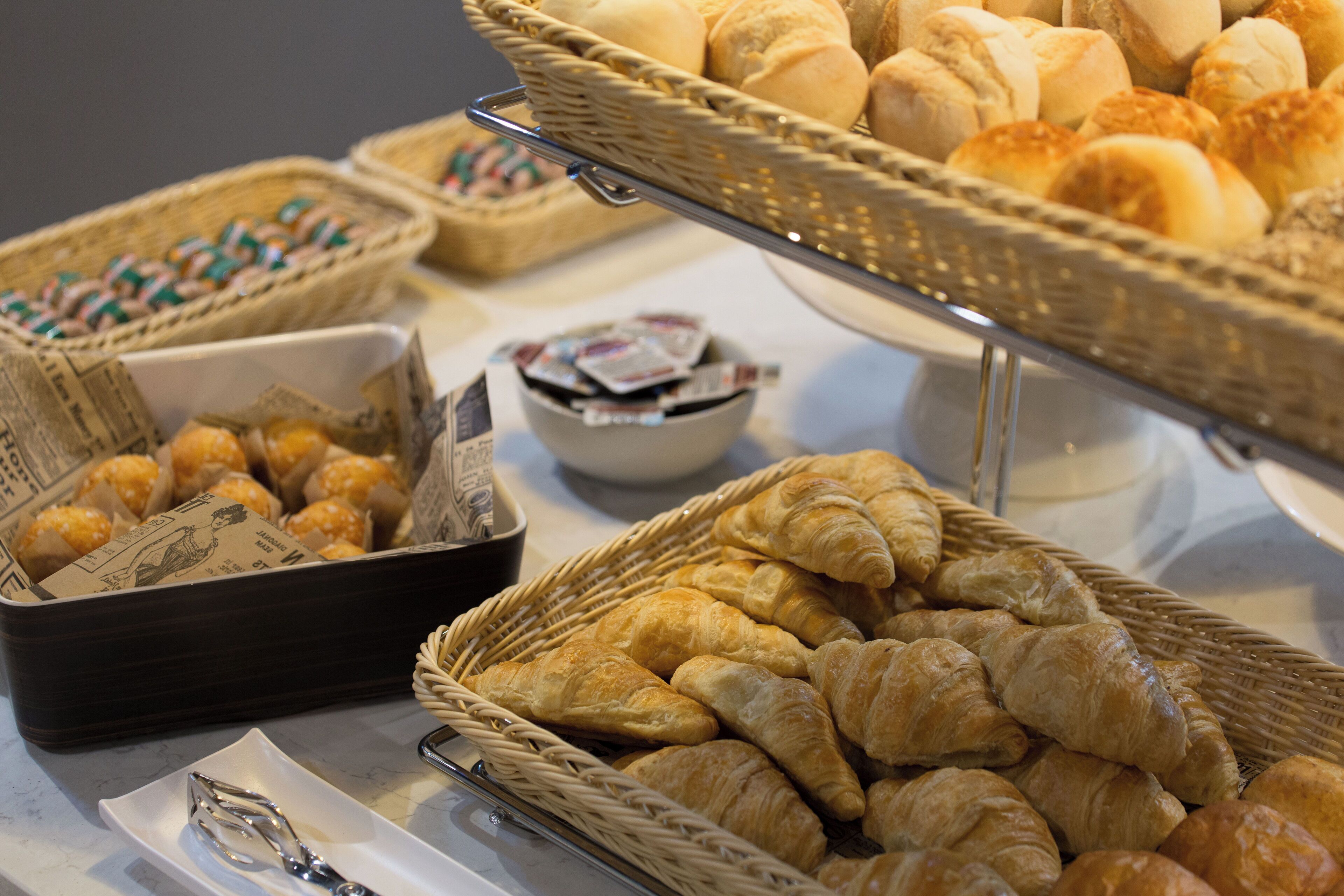 Buffet com diversos produtos de panificação, incluindo croissants e doces.