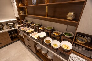 Disposição de buffet com diversos pratos e utensílios.
