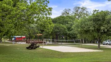 Um parque com uma rede de voleibol, mesas para piquenique e um cesto de basquete.