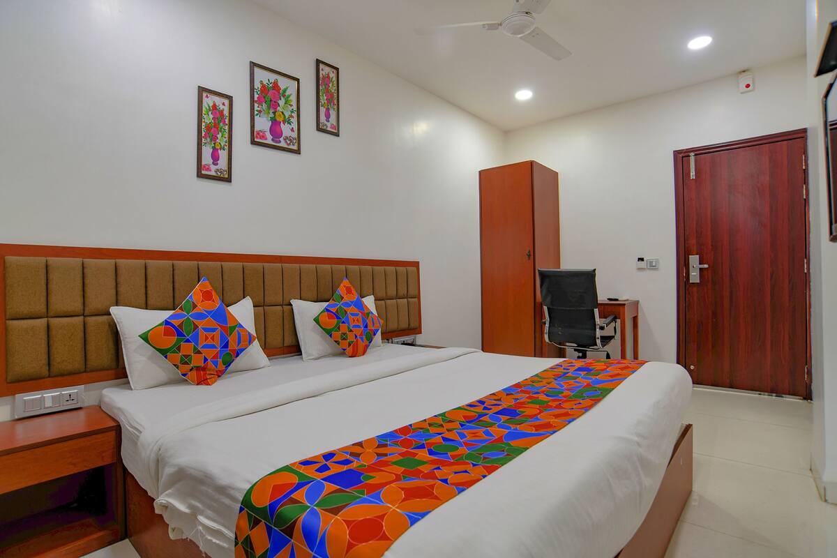 Quarto de hotel com cama, guarda-roupa, escrivaninha e cadeira.
