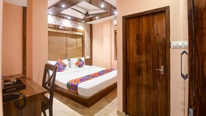 Quarto com cama, porta de madeira e ventoinha no teto.
