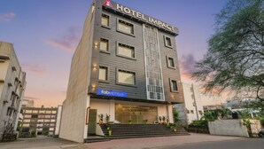 Um edifício moderno de hotel com uma placa grande 'HOTEL IMPACT', uma placa 'fabHOTELS' e uma escadaria que leva à entrada.