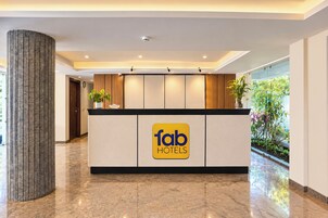 Bancada de recepção com o logotipo 'fab hotels' e um vaso de planta em cima.